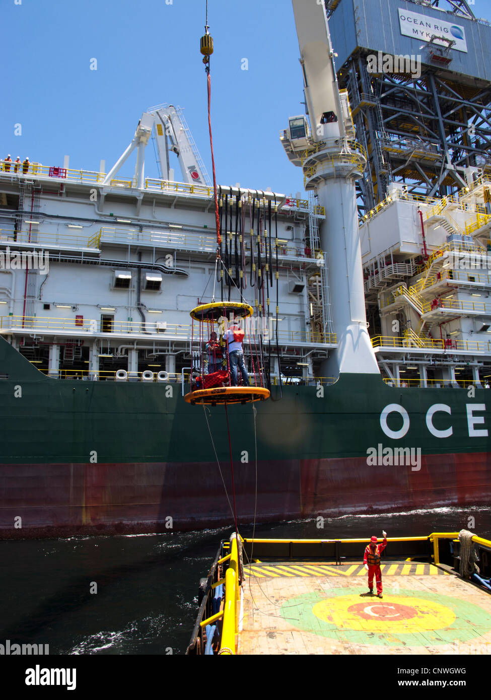 Crew member been transfered from an oil rig in a basket for a crew boat ...