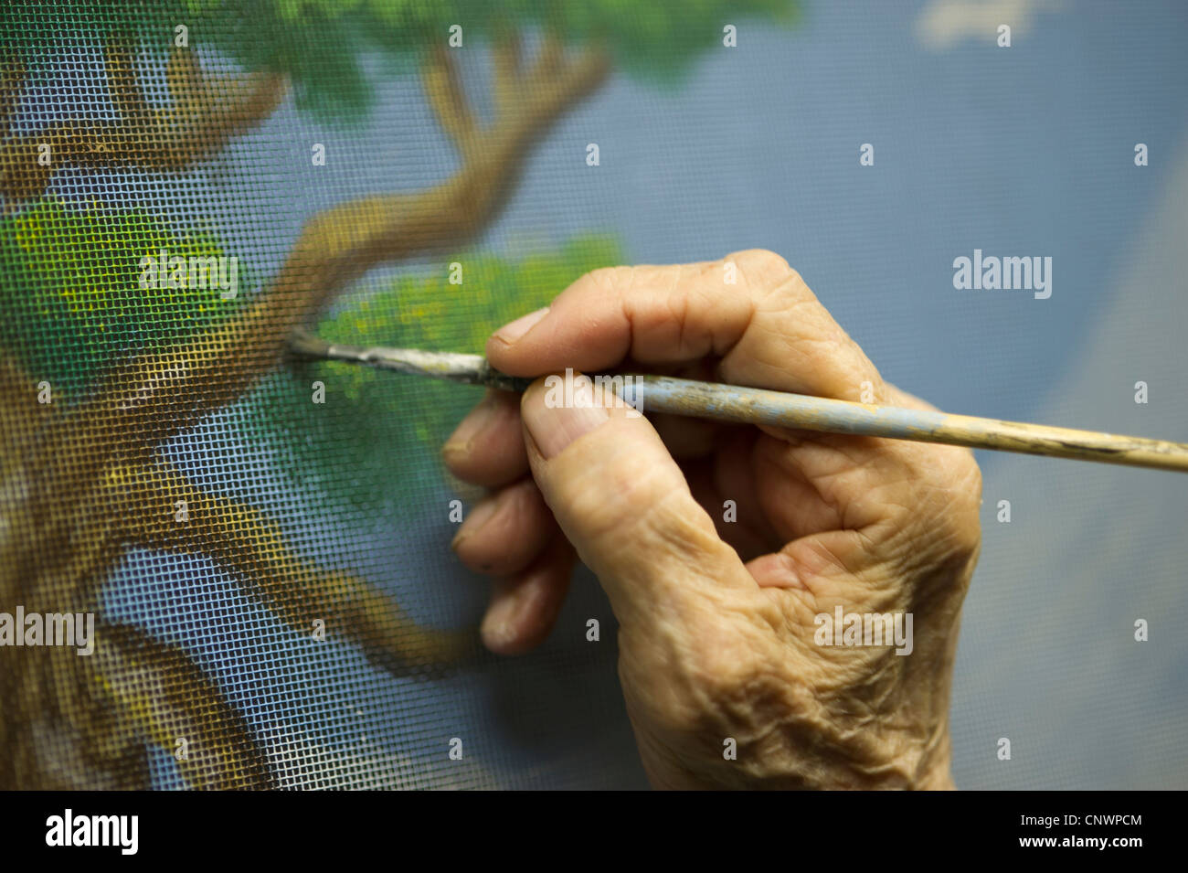 Artist holding her paintbrush painting a screen in traditional style of ...