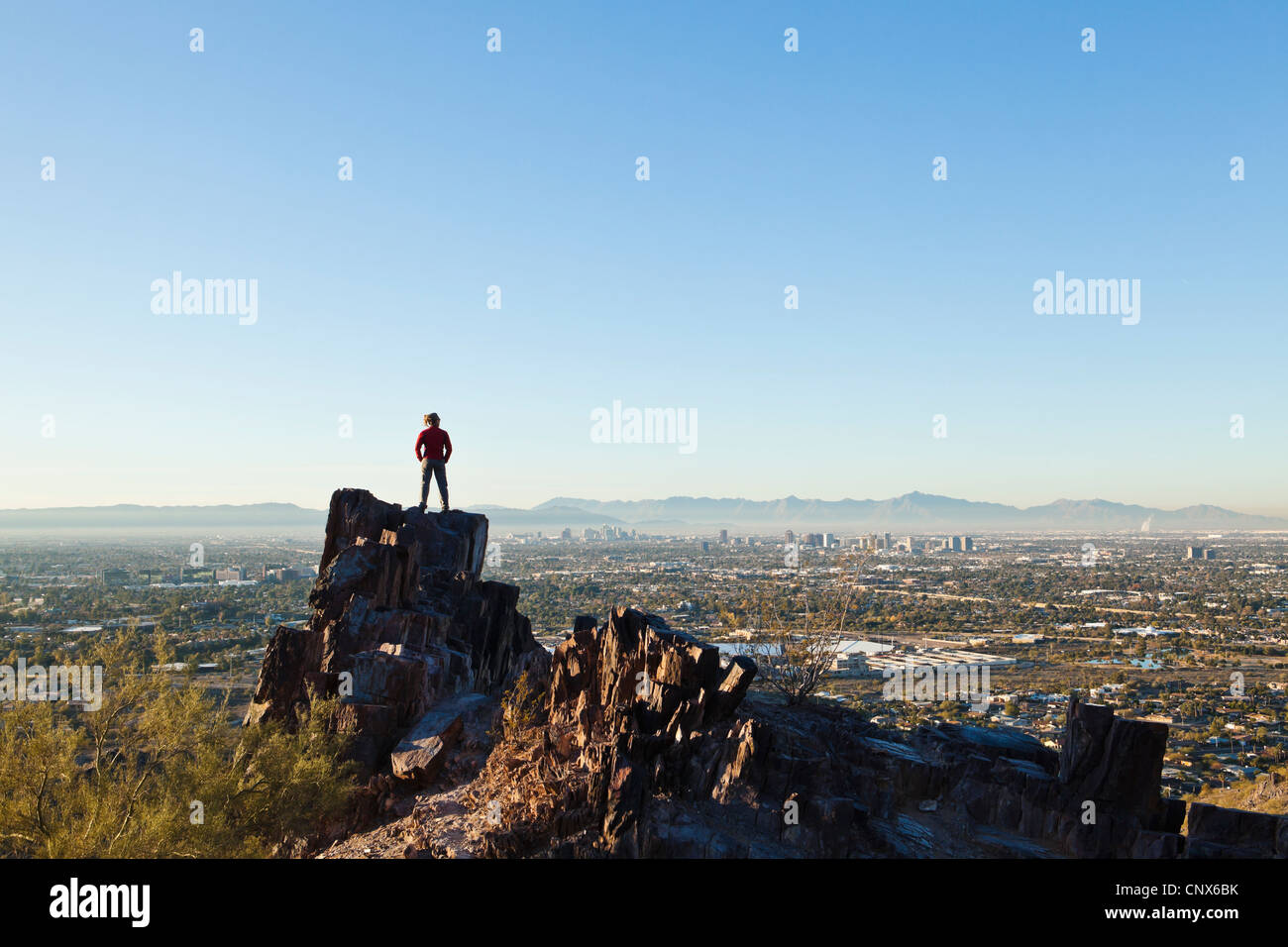A woman stands atop a rocky outcrop on Piestewa Peak overlooking ...