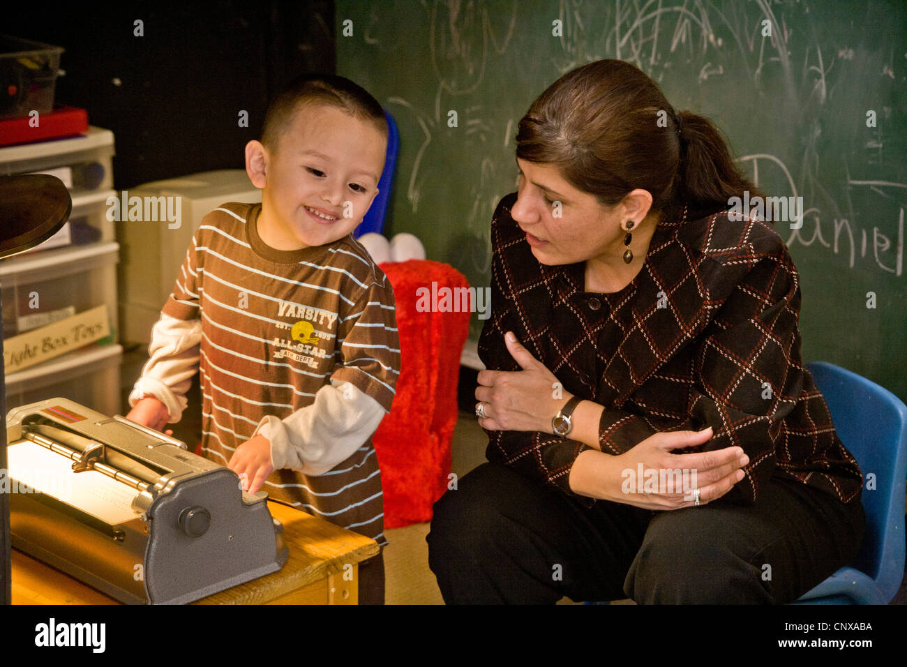 With the help of a trained staff member a blind boy types on a Braille ...
