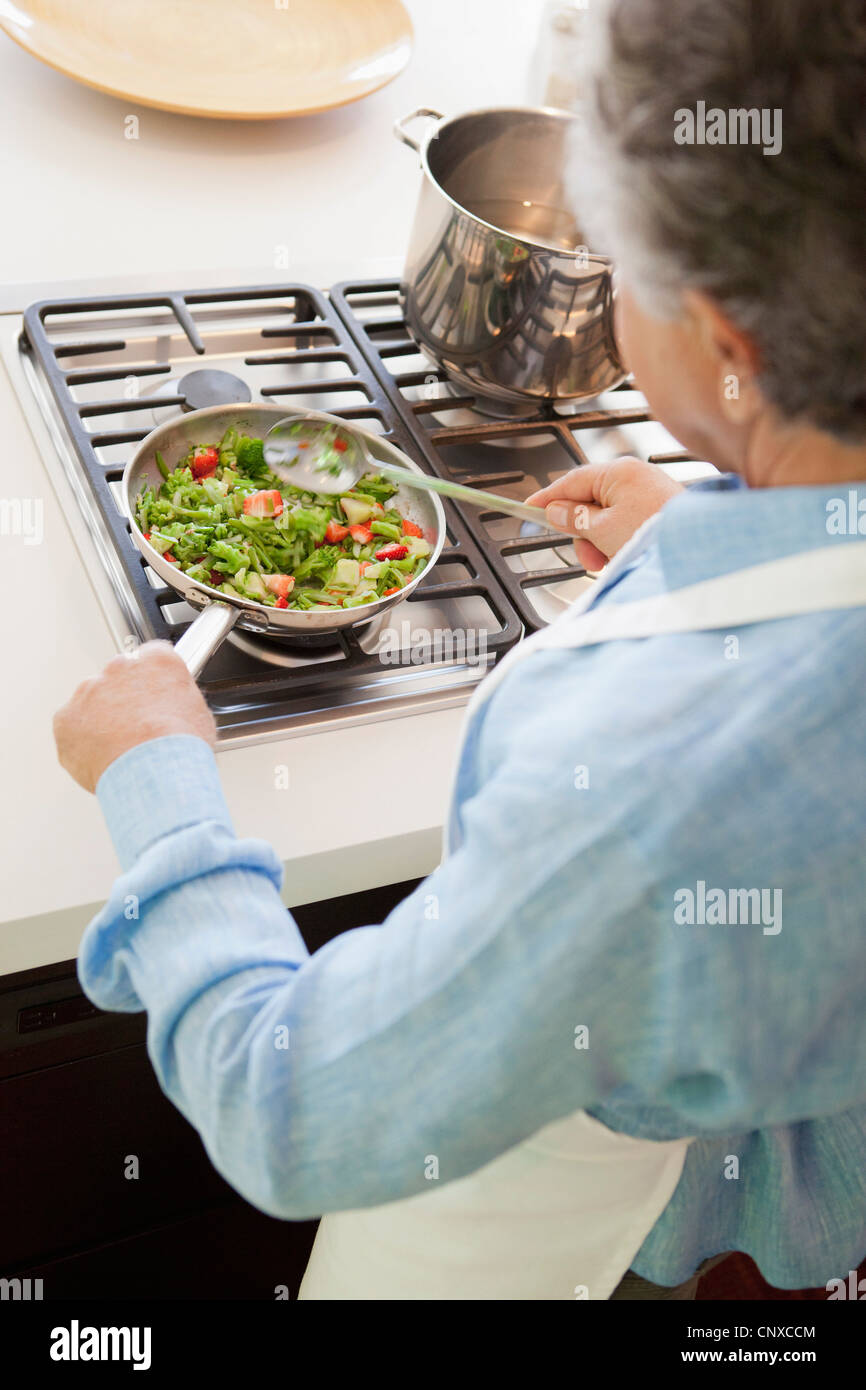 Over the shoulder view of a senior man cooking vegetables Stock Photo ...