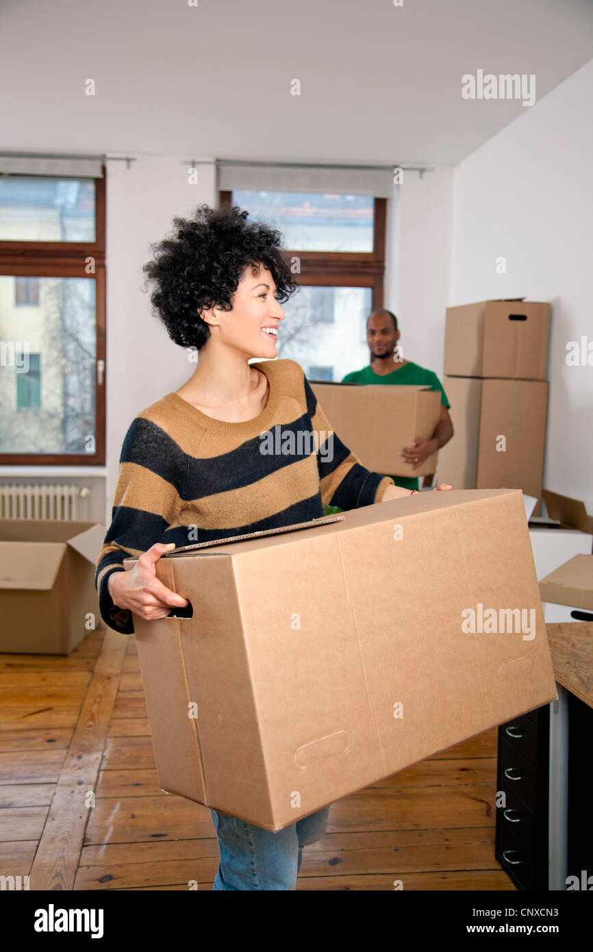 A man and woman carrying moving boxes, focus on woman Stock Photo - Alamy