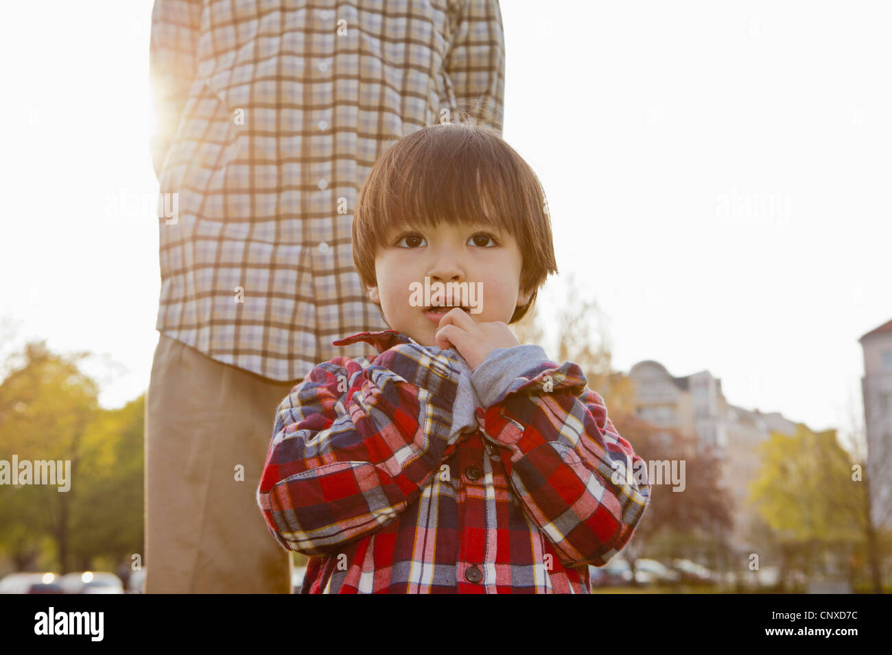 A boy standing in front of his father Stock Photo - Alamy