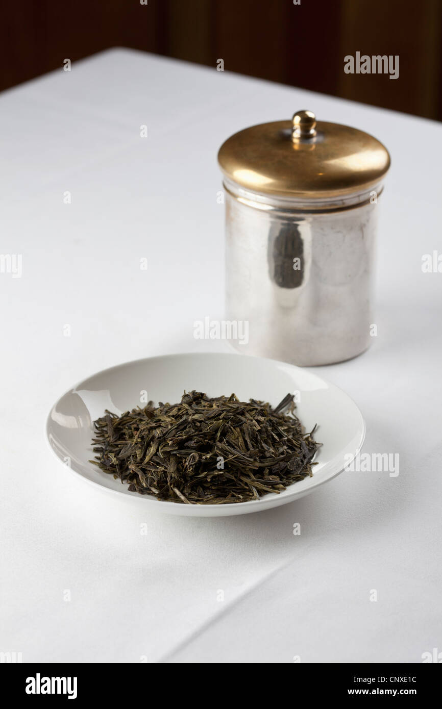 Green tea leaves in a dish next to a canister Stock Photo - Alamy