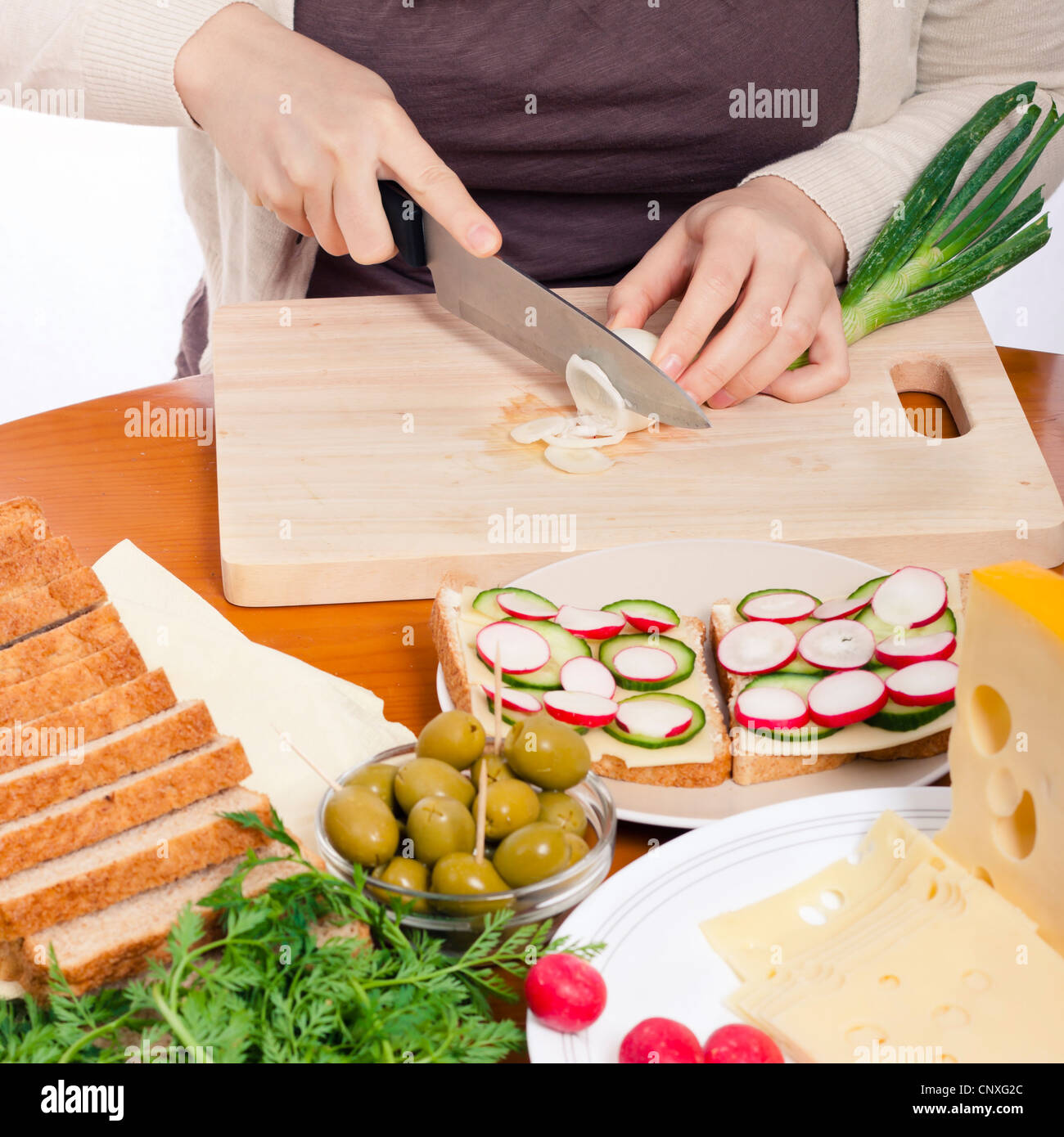 Detail of woman chopping fresh spring onion and preparing sandwiches ...