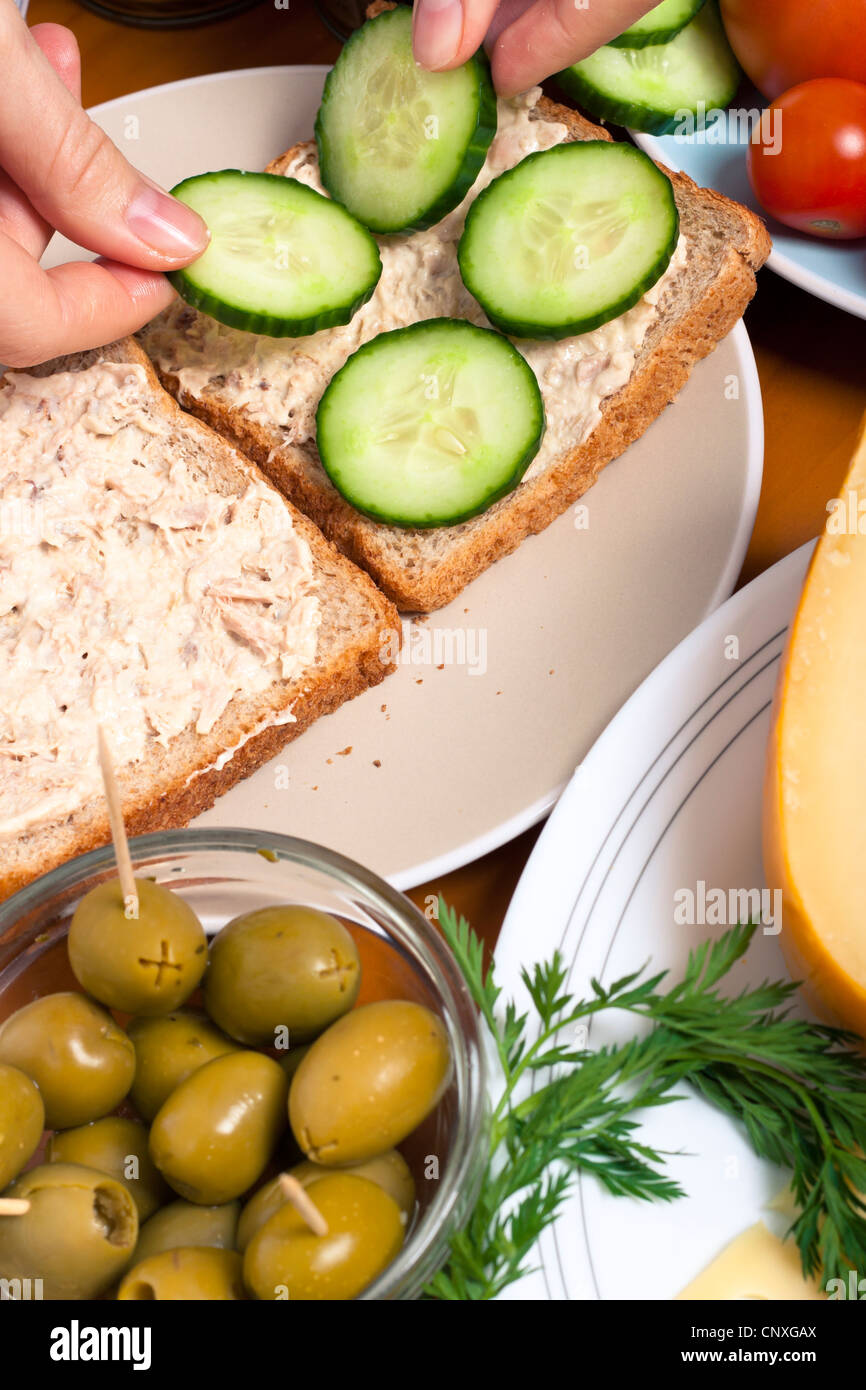 Detail of table with food and female hands putting slices of cucumber ...