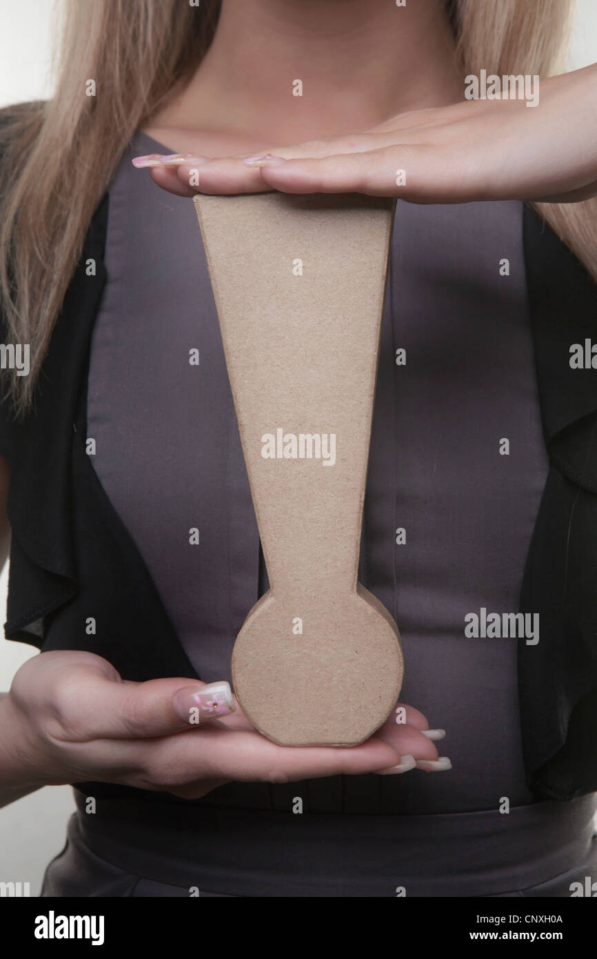 woman holding up a exclamation mark to her chest Stock Photo - Alamy