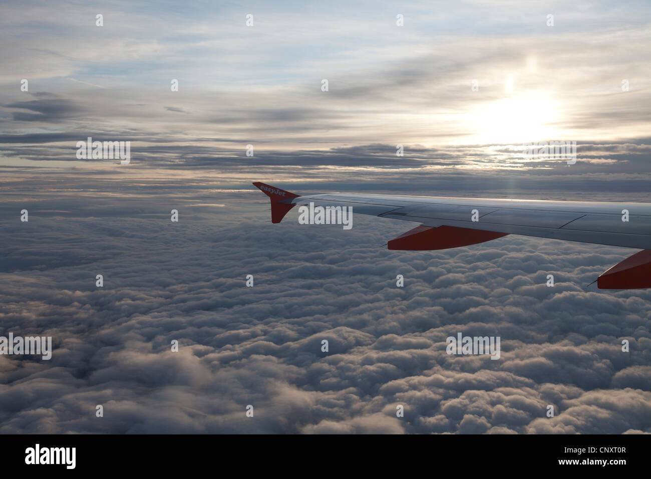 Easyjet aircraft wing above blanket of cloud with rising sun Stock ...