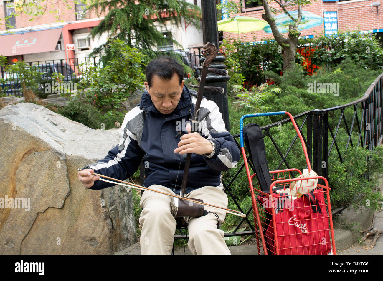 An Asian man busker playing an erhu, the two-string Chinese fiddle ...