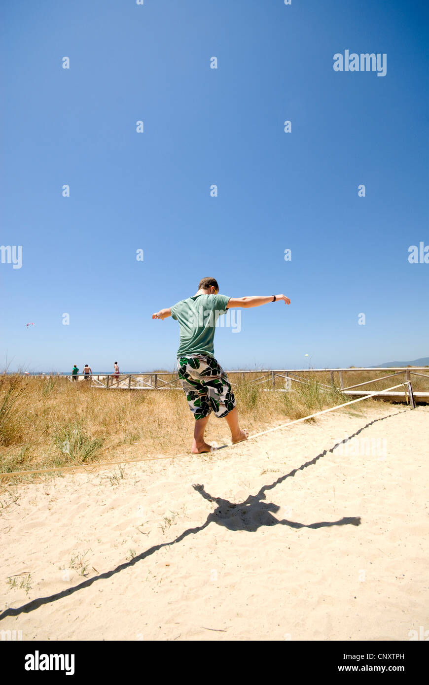 Teenagers walking tightrope at beach bar Stock Photo - Alamy