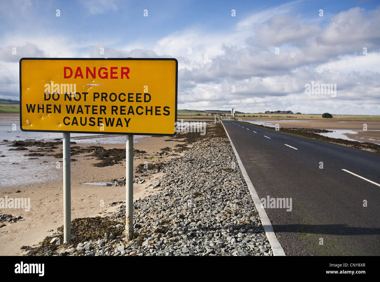 A danger sign on the causeway at Lindisfarne looking from the island ...