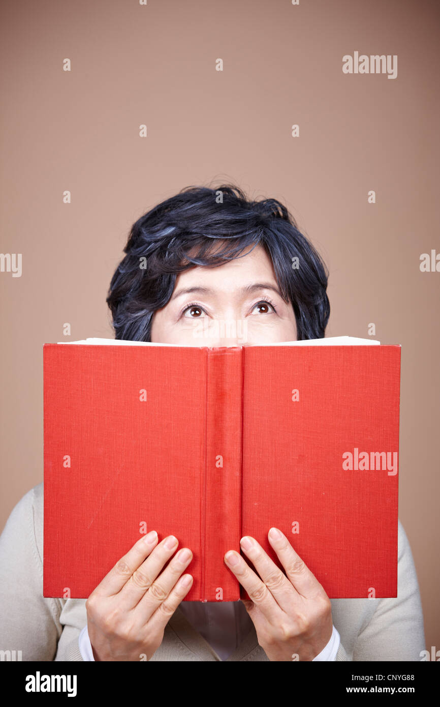 An old woman looking up with red book Stock Photo - Alamy