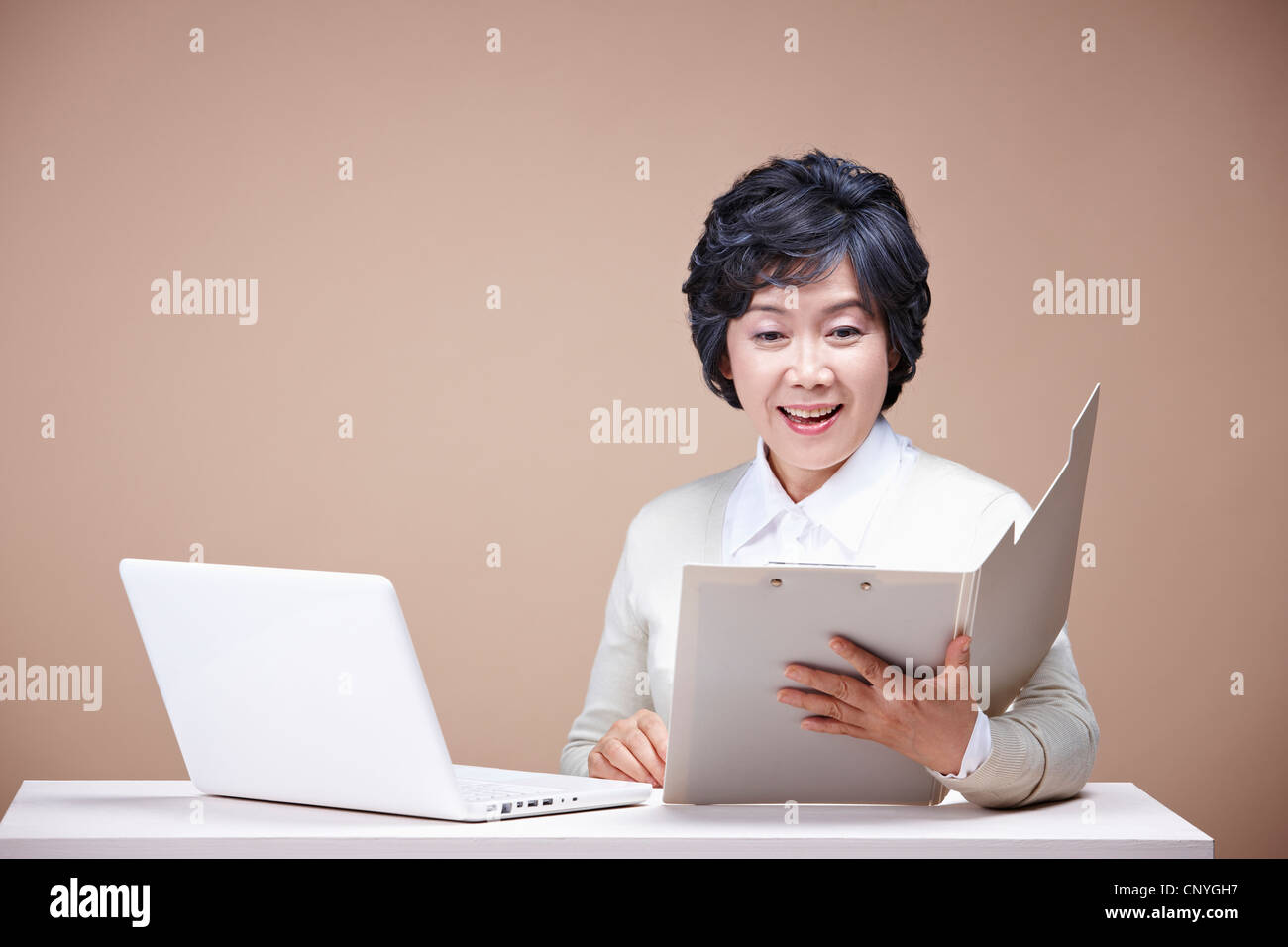 An old woman looking at document with laptop around Stock Photo - Alamy