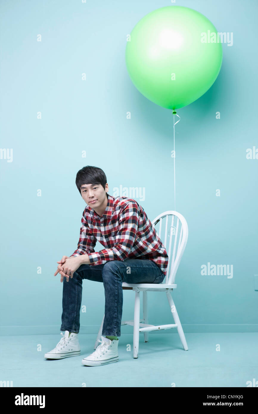 A man sitting with green balloon Stock Photo - Alamy