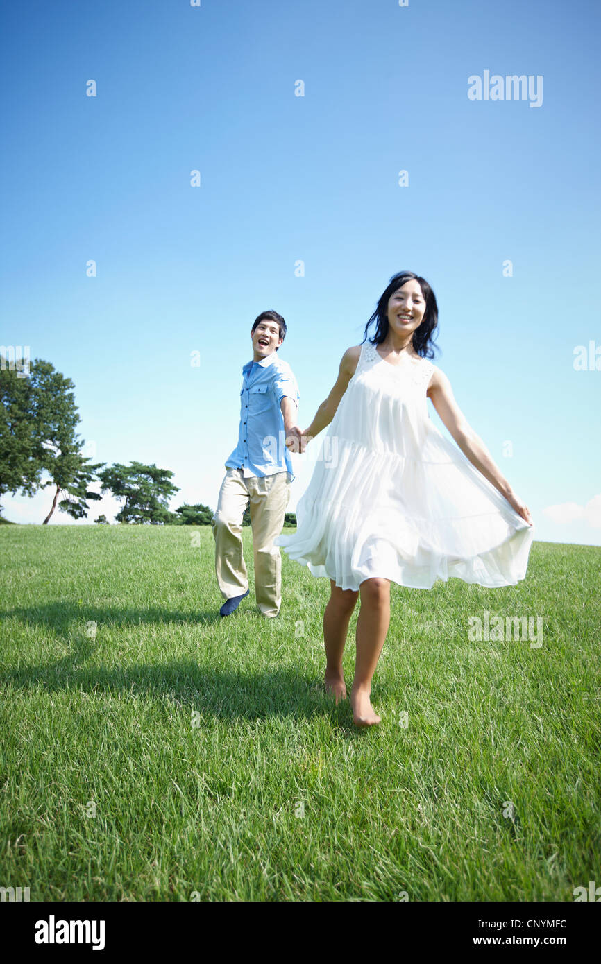 A couple running together in green field Stock Photo - Alamy
