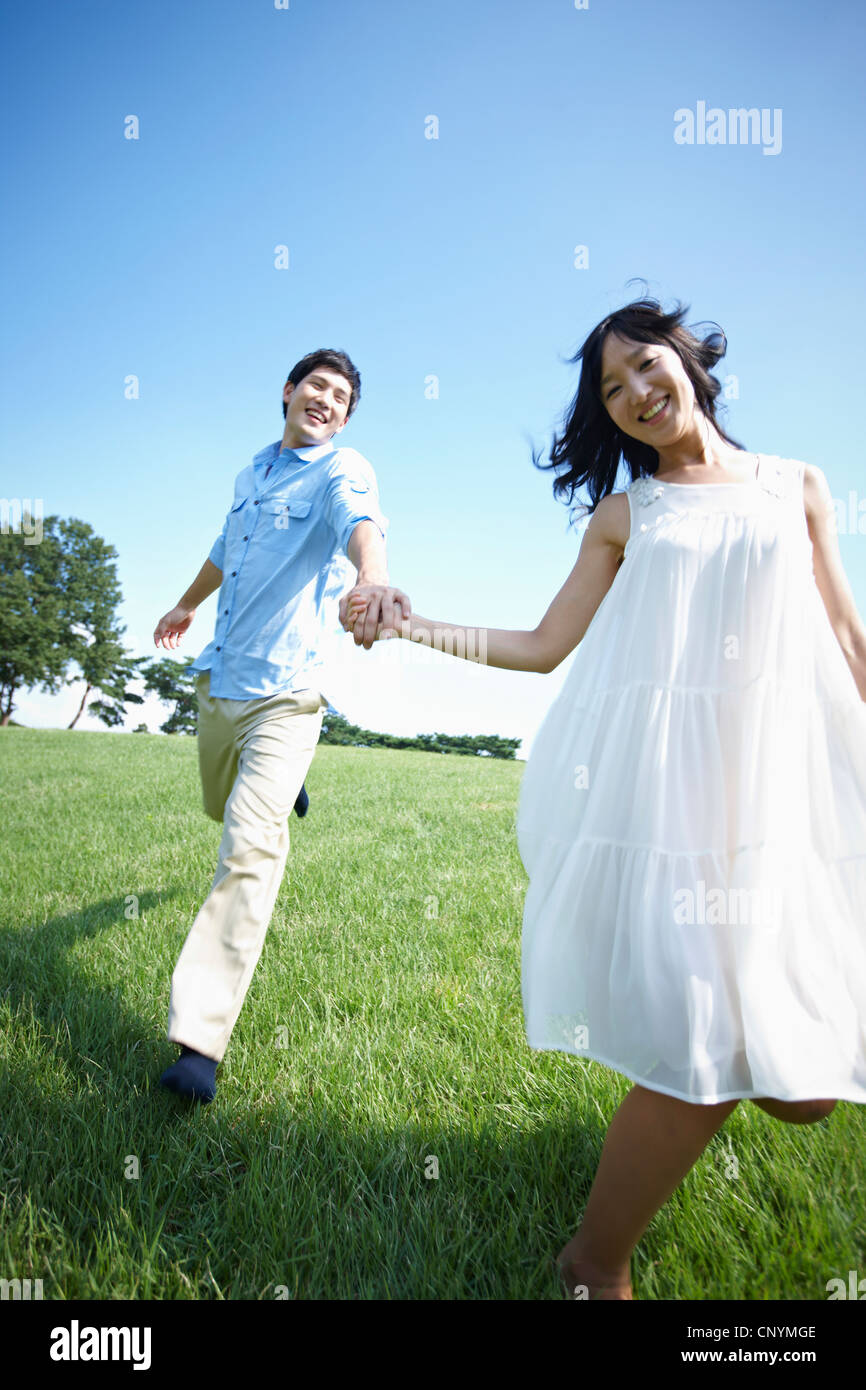 A couple running together in green field Stock Photo - Alamy