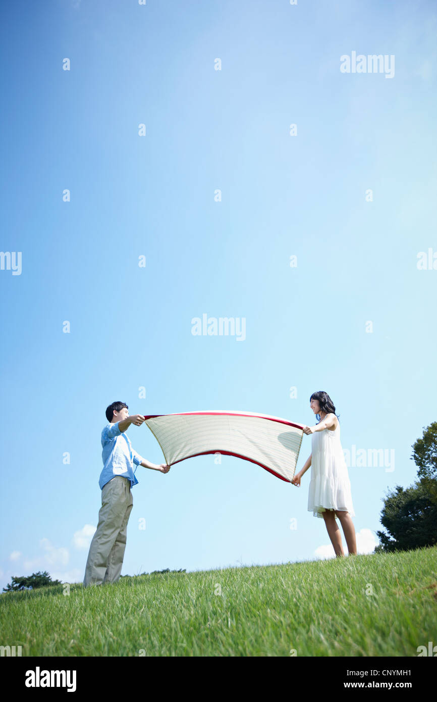 A couple spreading mat on green field Stock Photo - Alamy