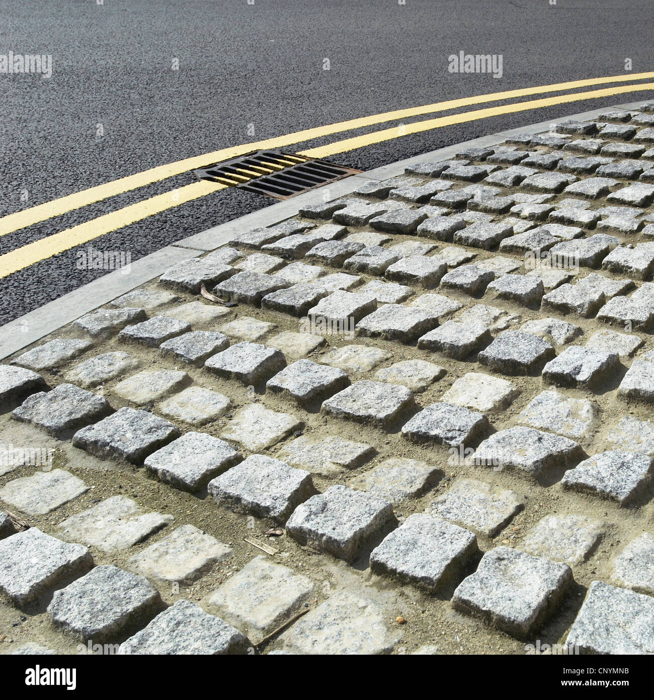 Stone cobbled surface next to a tarmac coated road Stock Photo - Alamy