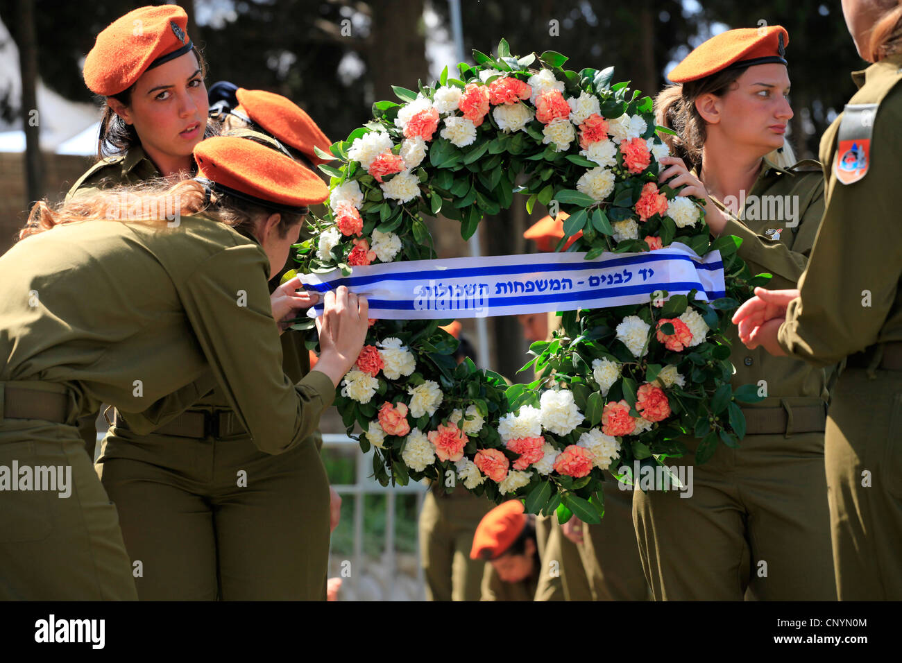An Israeli female soldier adjusts a ribbon over a wreath during a ...