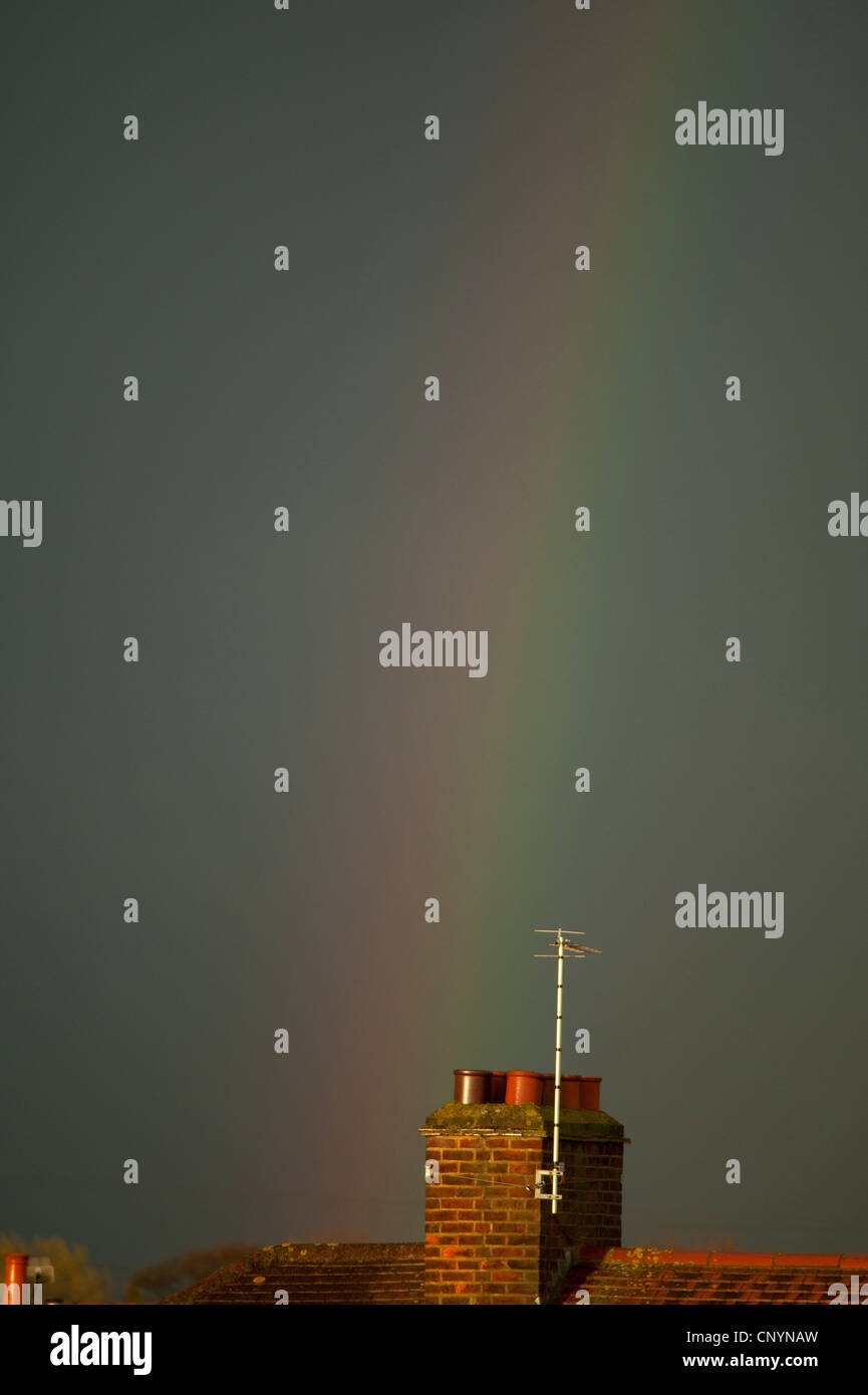 Rainbow over house rooftop with grey sky Stock Photo - Alamy