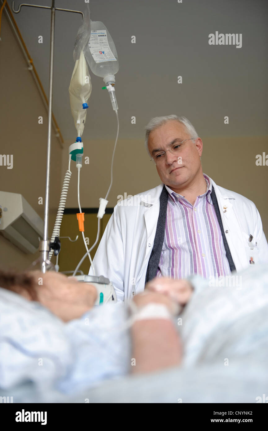 Doctor next to patient's bed in hospital ward Stock Photo - Alamy