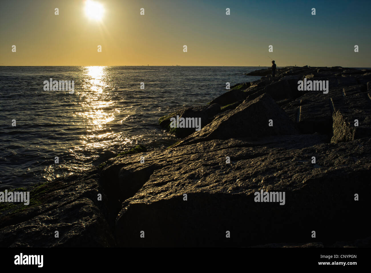 Fisherman fishing at rocky pier jetties Stock Photo - Alamy