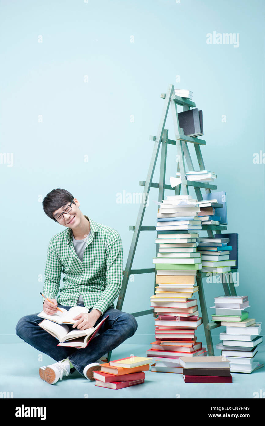 A studying man by the piled books and ladder Stock Photo - Alamy