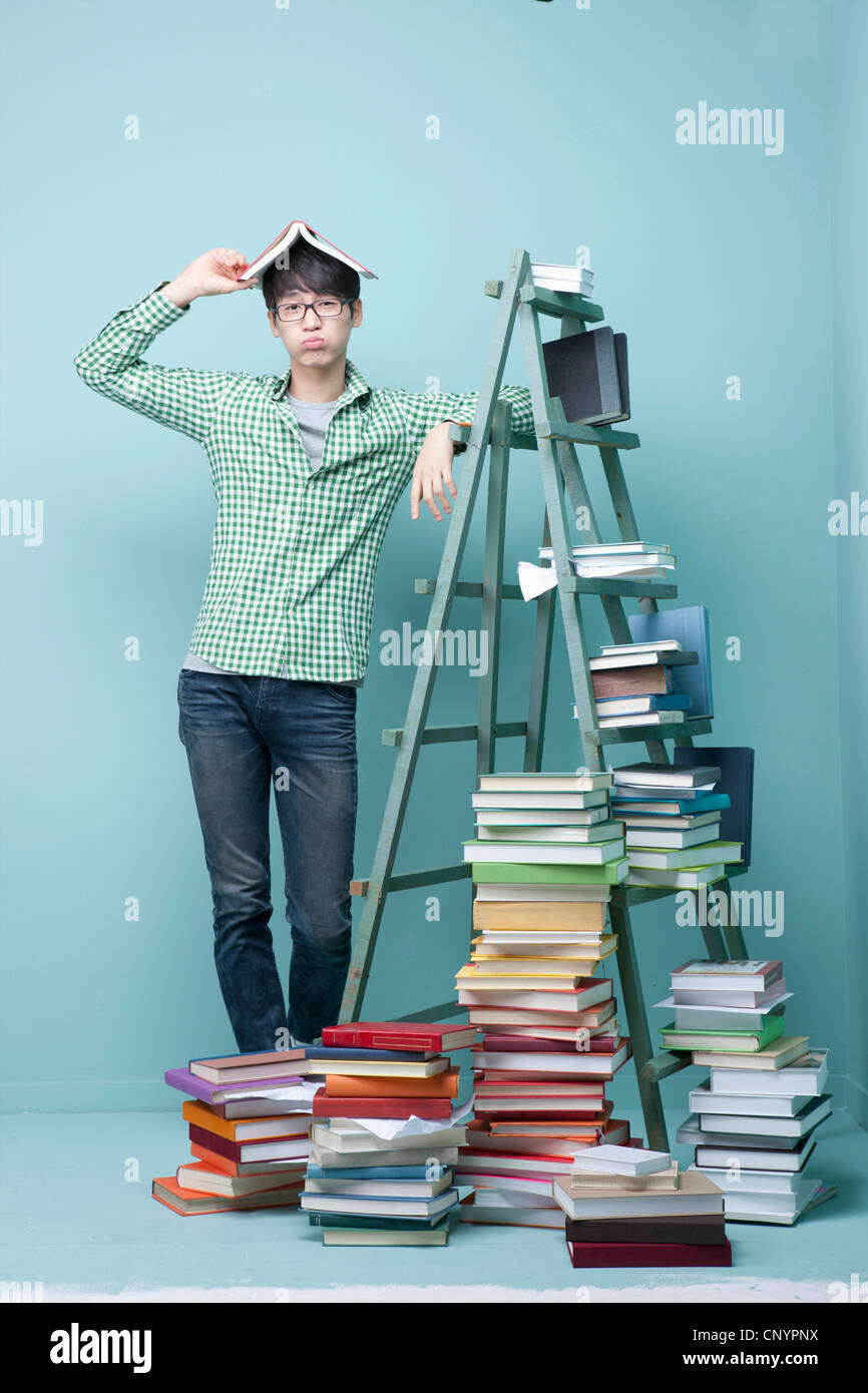 A studying man by the piled books and ladder Stock Photo - Alamy