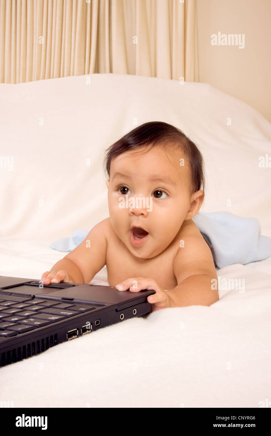 Kid playing with notebook computer keyboard, typing on it Stock Photo ...