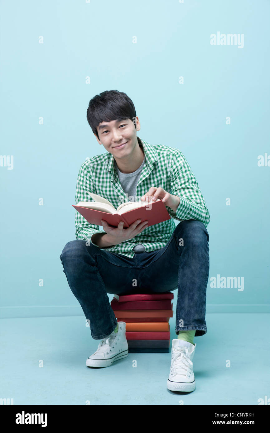 A man reading a book on the piled books Stock Photo - Alamy