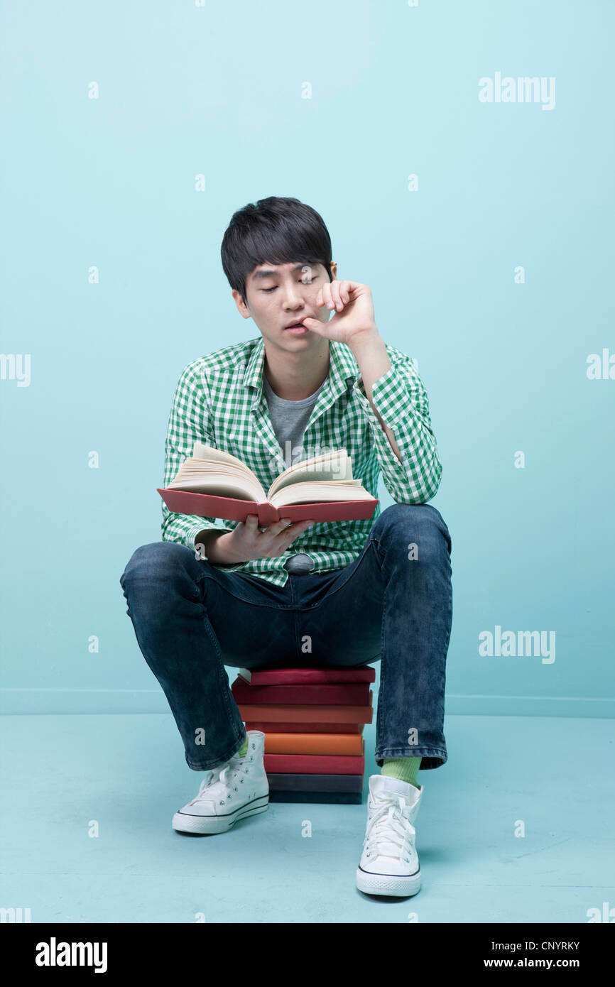 A man reading a book on the piled books Stock Photo - Alamy