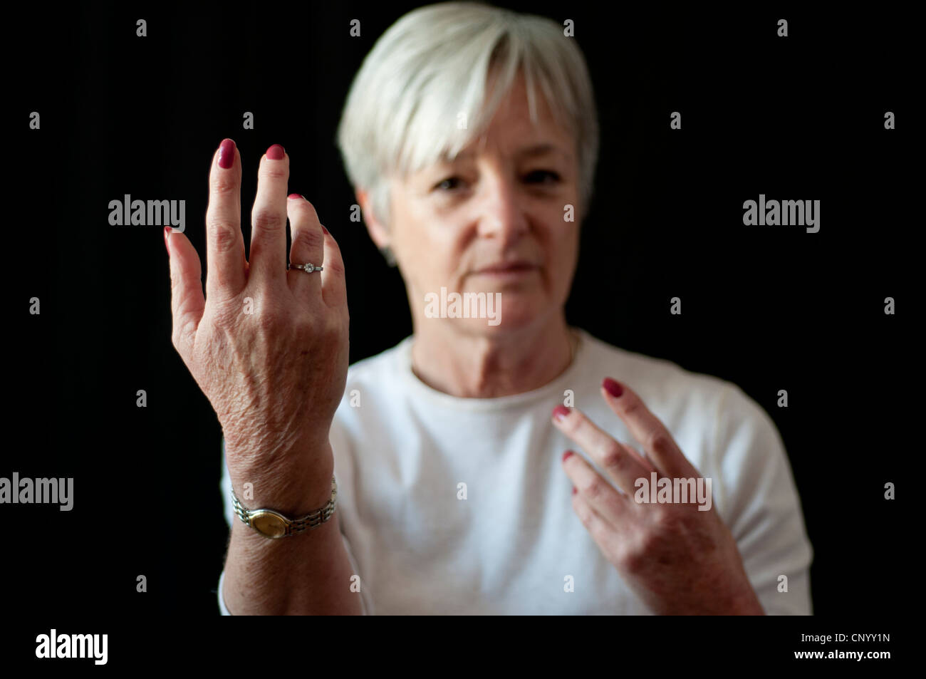 Middle aged woman with raised hand in focus Stock Photo - Alamy