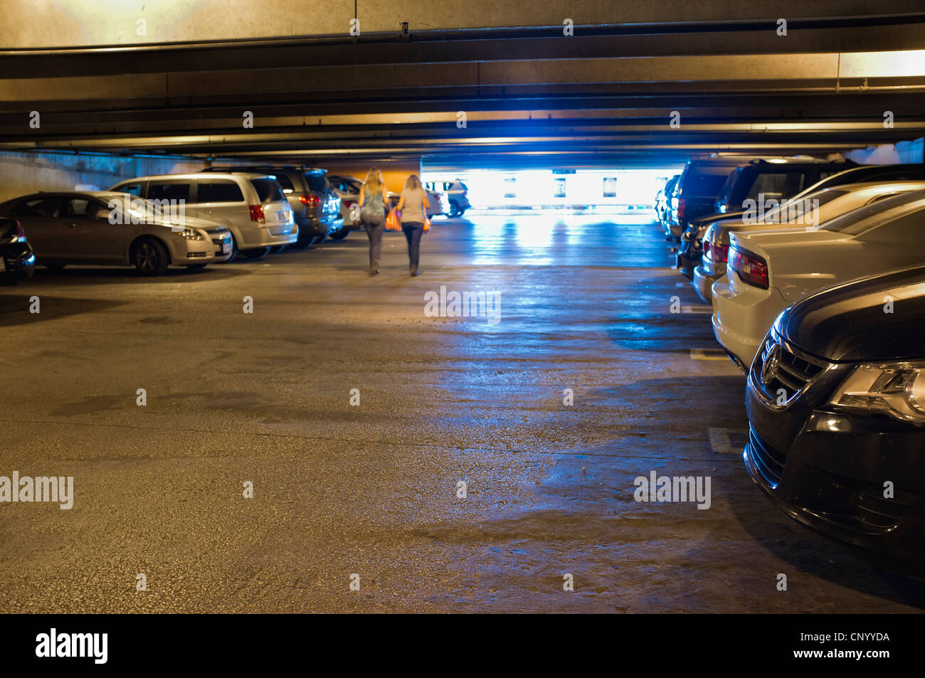 Inside a parking garage building with two women walking to their car ...