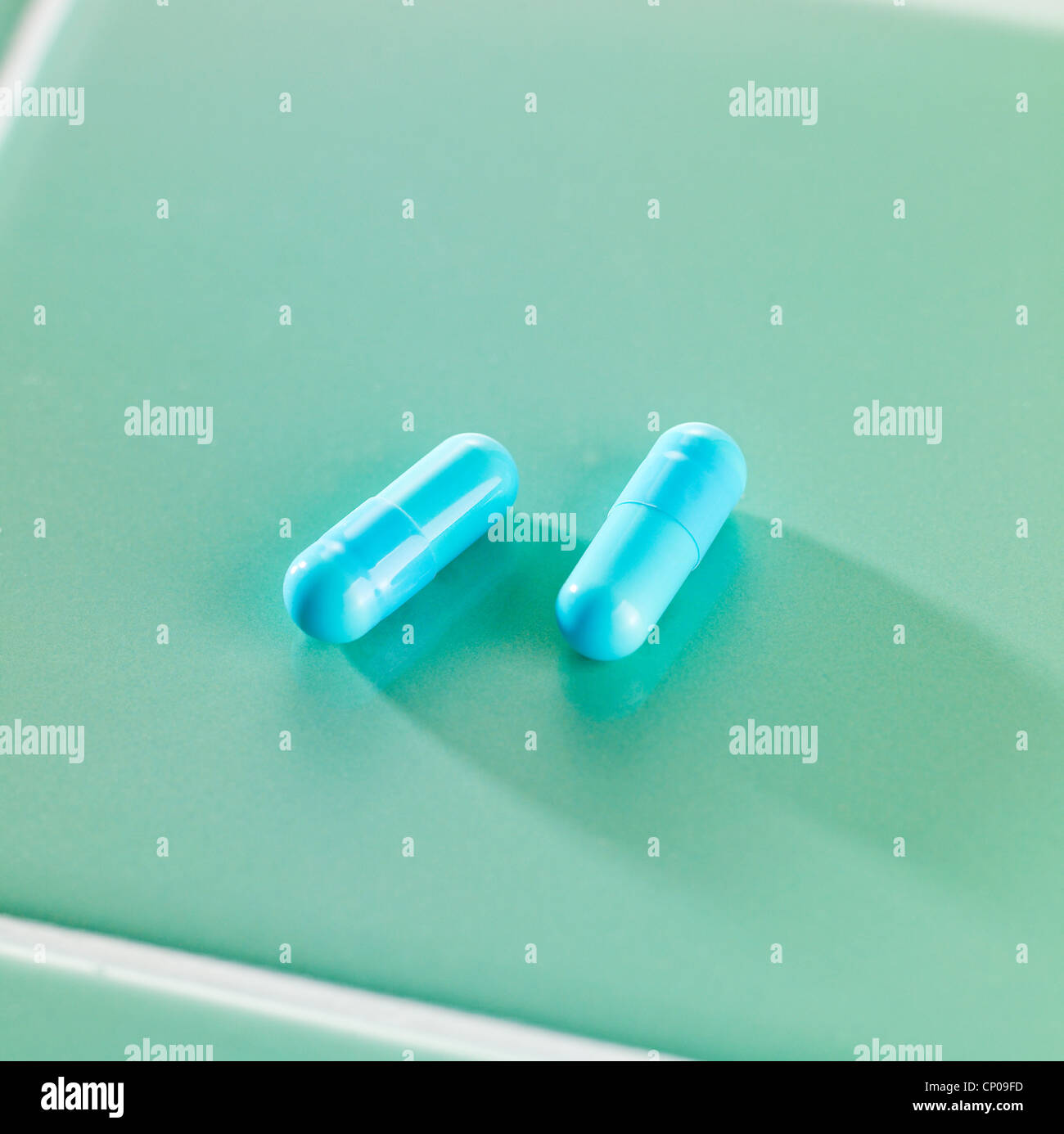 Little Blue pills on an aqua tile background Stock Photo - Alamy