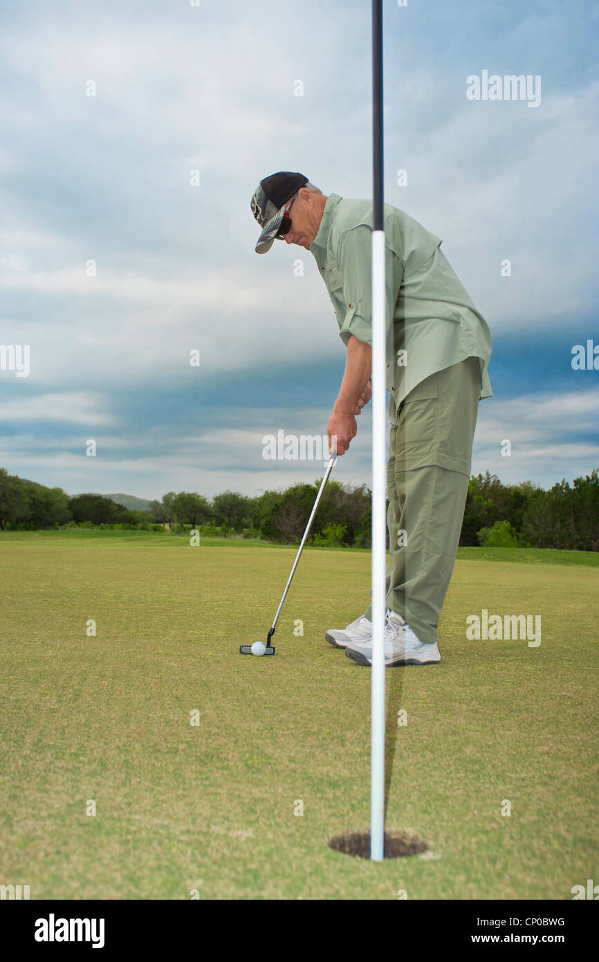 Golfer using putter at golf game Stock Photo - Alamy