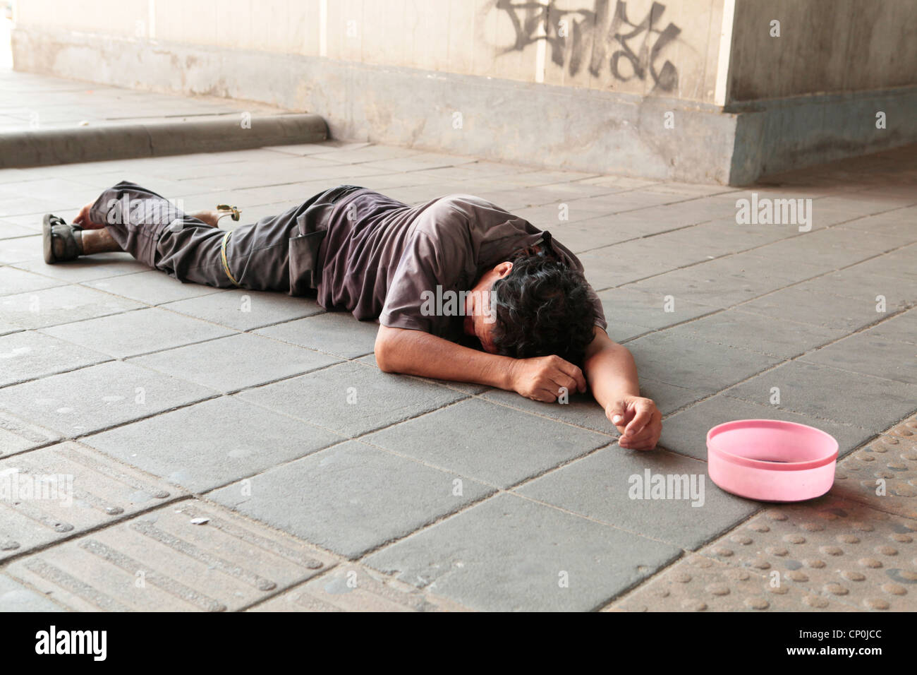 This image shows a disabled beggar with a missing leg and his bowl ...