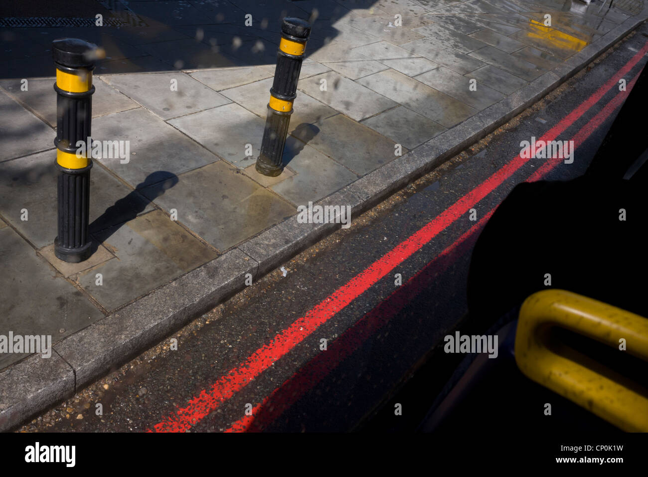 Traffic bollards and red route stripes outside of a London bus window ...