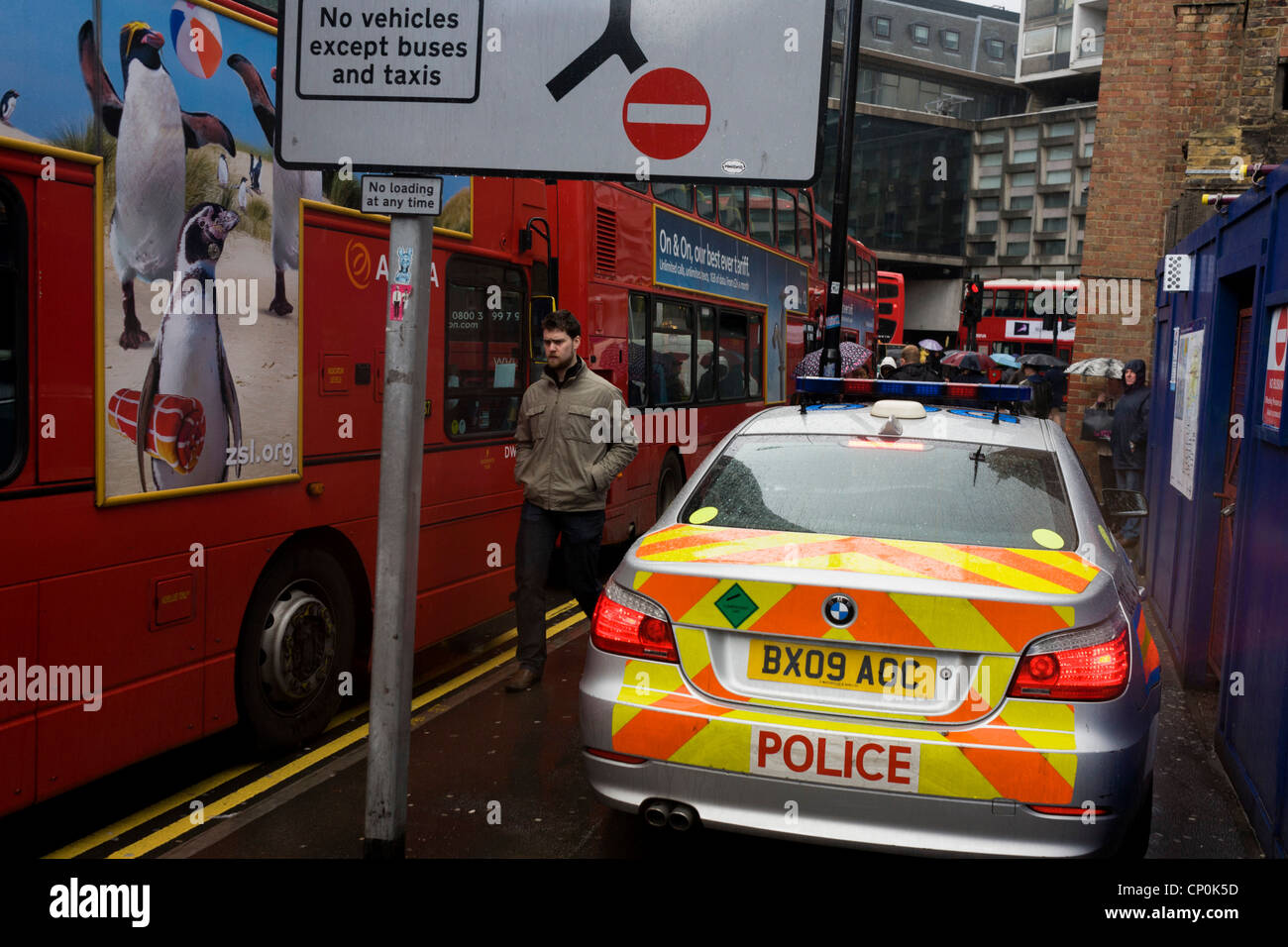 A Metropolitan police car drives carefully past pedestrians and ...