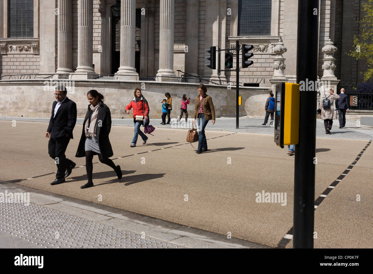 Pedestrians walk across a road crossing point below the pillars and ...