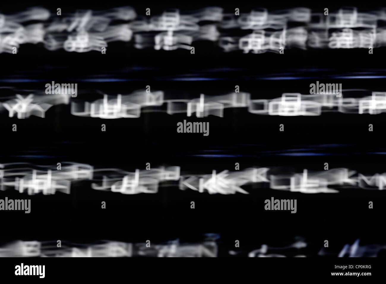 Black computer keyboard with blurry illuminated backlit white letters ...