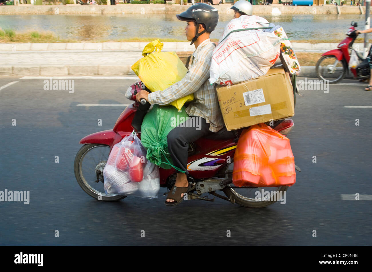 Horizontal close up of a man driving a moped overloaded with boxes and ...
