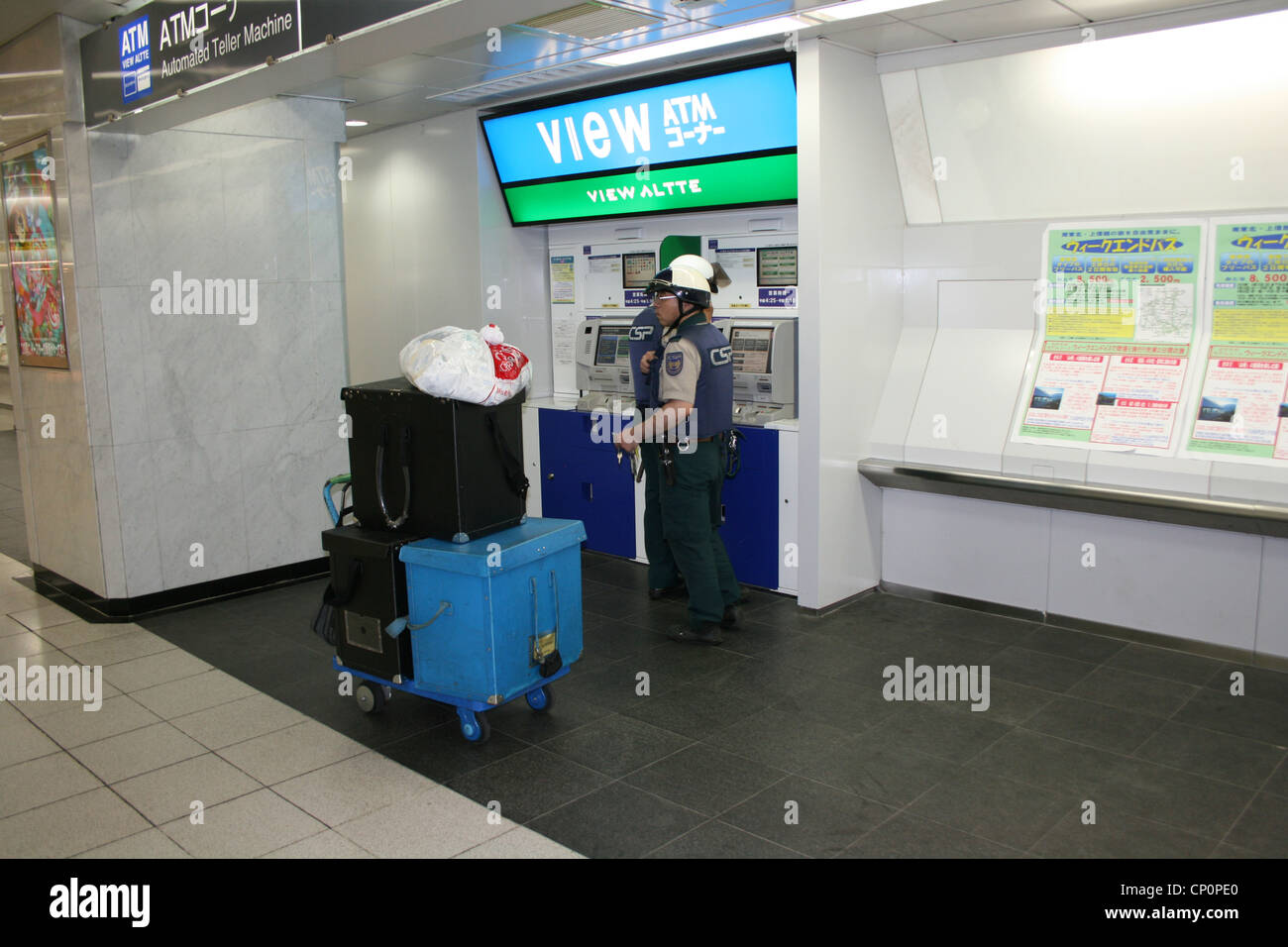 Guard in a Tokyo train station guards money transfer at ATM and ticket ...