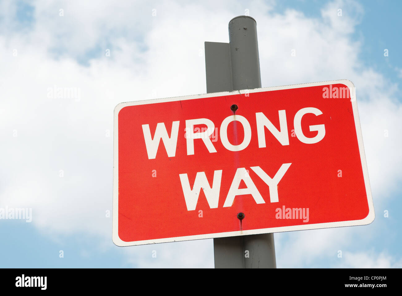 Wrong Way sign post against a cloudy blue sky. Can be used as a ...
