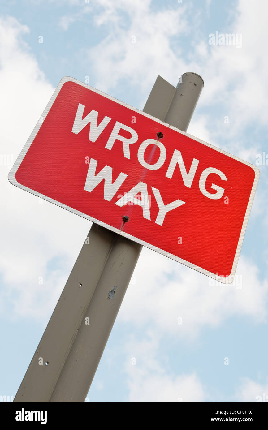 Wrong Way sign post against a cloudy blue sky. Can be used as a ...