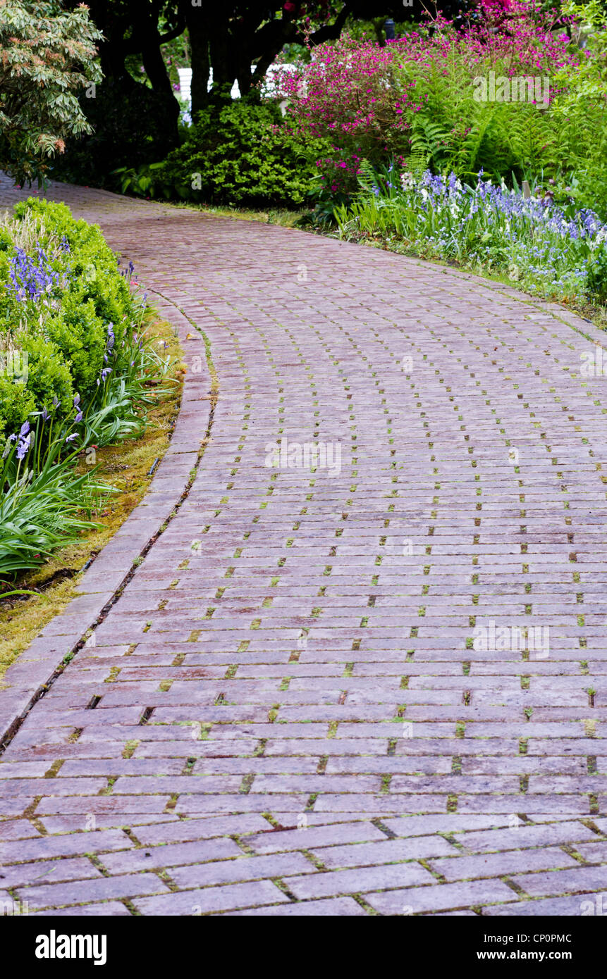 A winding garden path of red pavers with flowers Stock Photo - Alamy