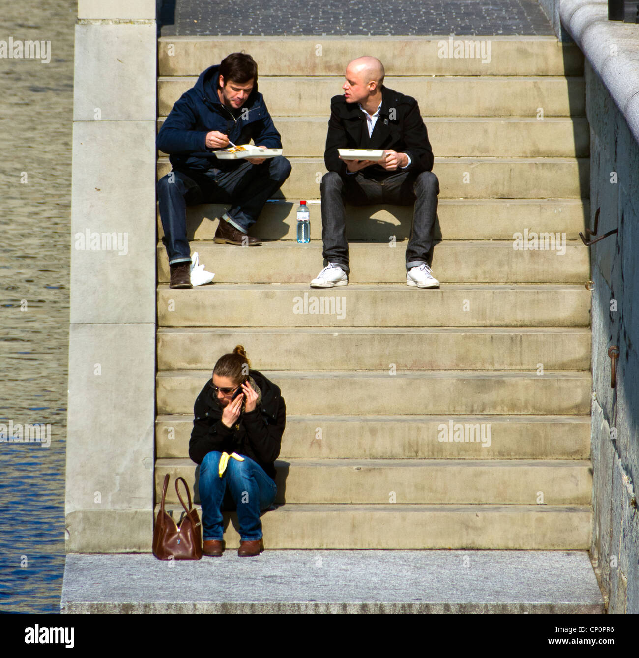 two men and a woman eating lunch on stairs in Zurich Stock Photo - Alamy