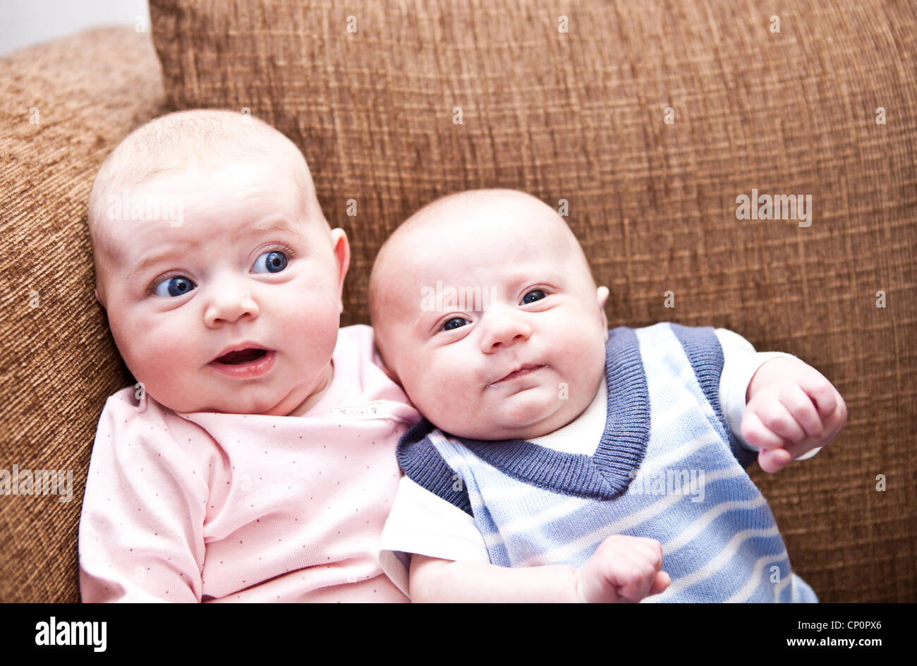 Two babies sitting on a couch with amusing expressions Stock Photo - Alamy