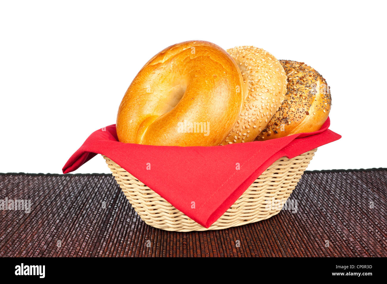A wicker basket with three bagels including a plain bagel, sesame seed ...