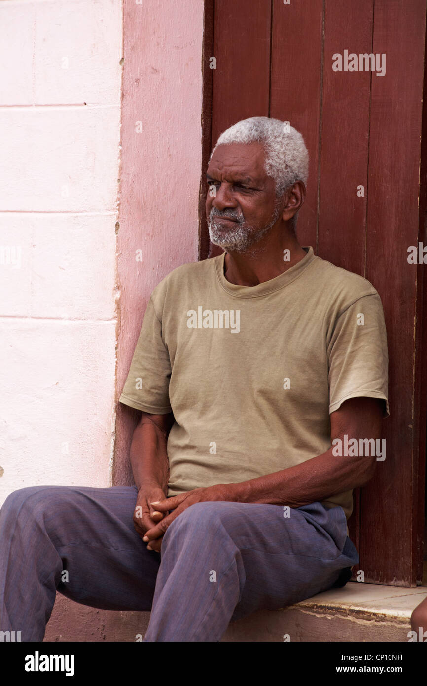 Daily life in Cuba - Afro-Caribbean man sat on steps in doorway at ...