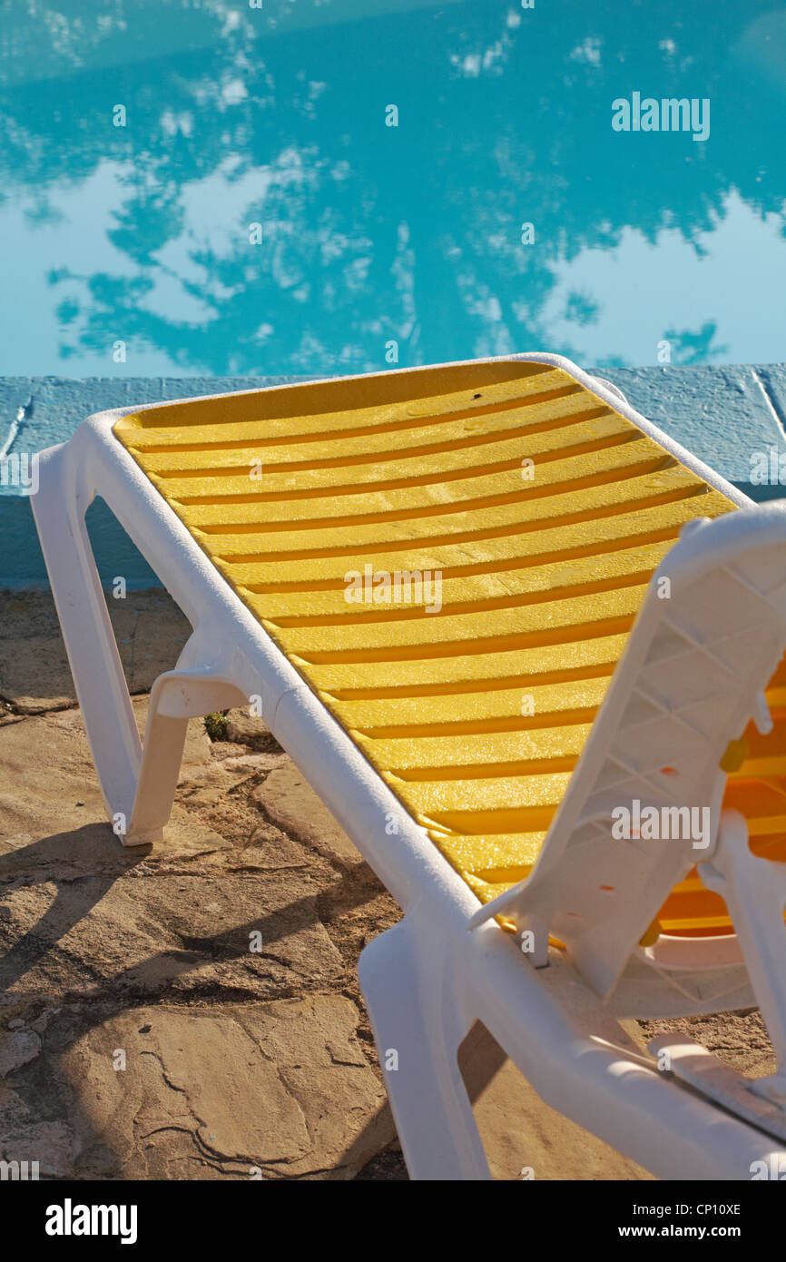 yellow sun lounger by side of swimming pool early in the morning with ...